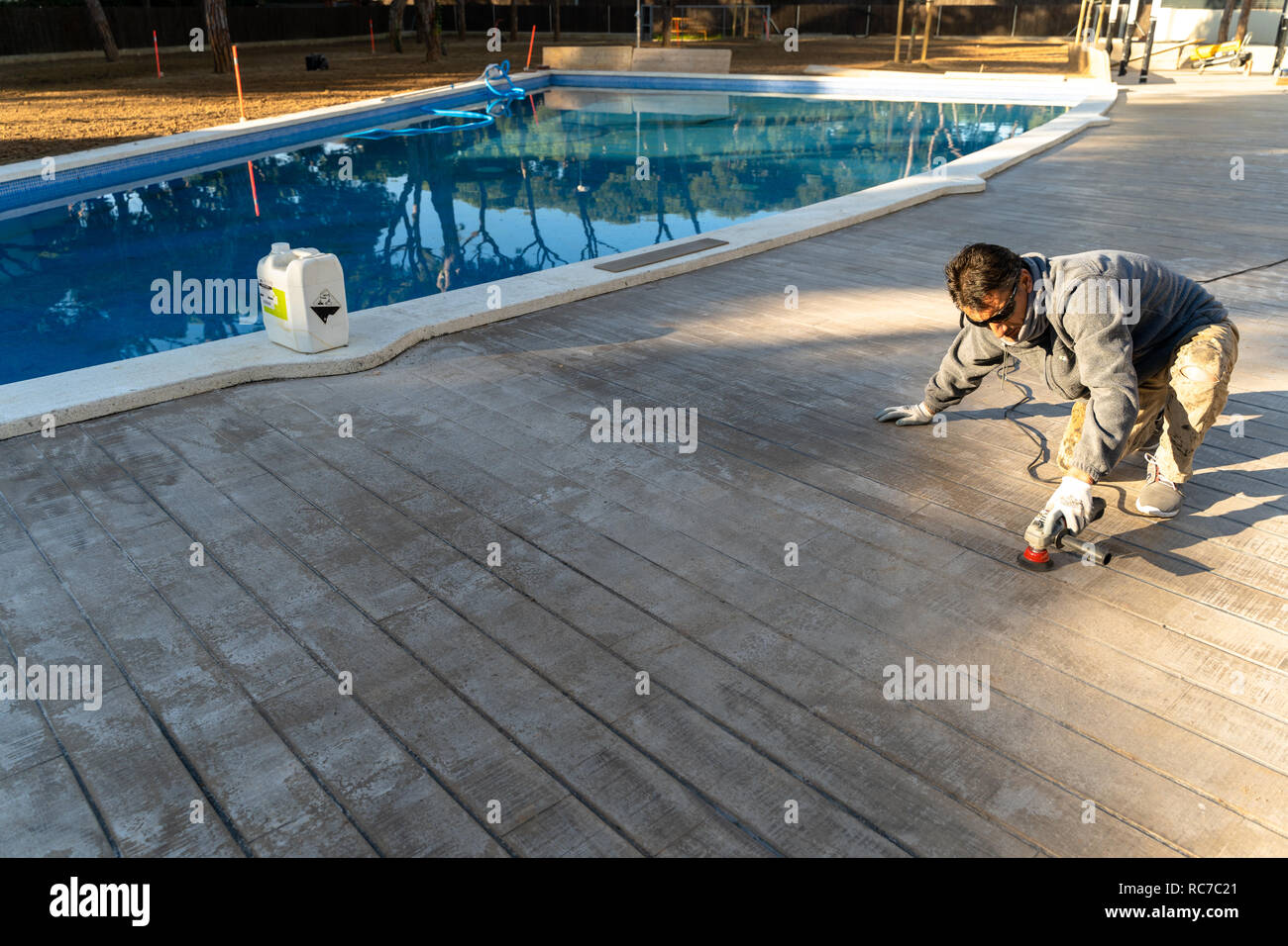 Construction worker sanding the floor with a grinder with a wire disk ...