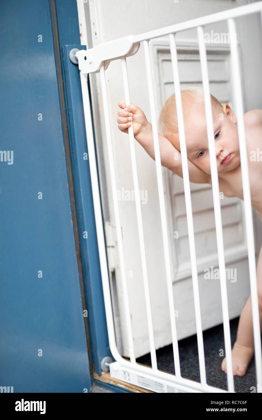 Baby boy looking through gate Stock Photo - Alamy