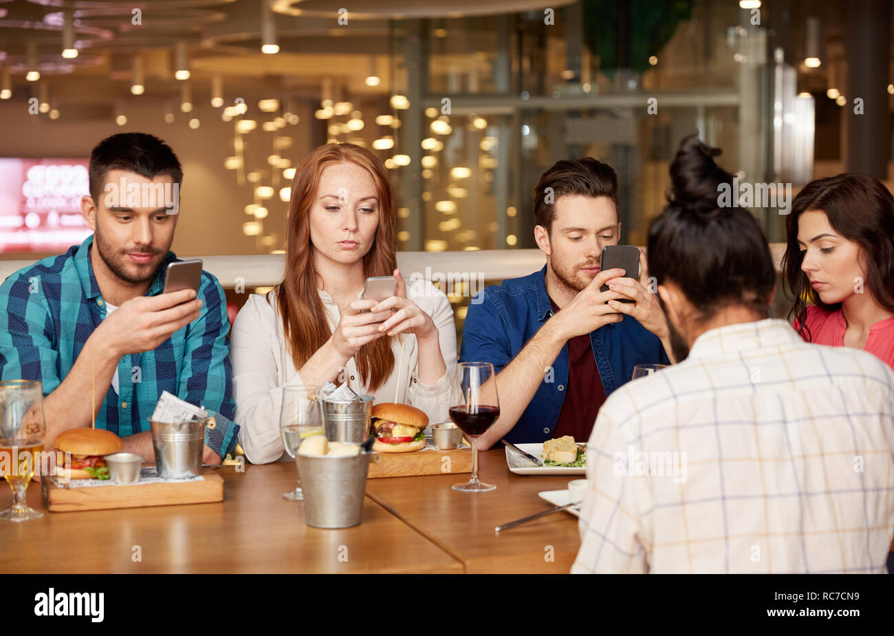 friends with smartphones at restaurant Stock Photo - Alamy