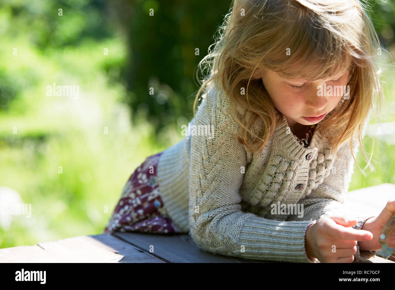 Girl leaning against table in backyard Stock Photo - Alamy