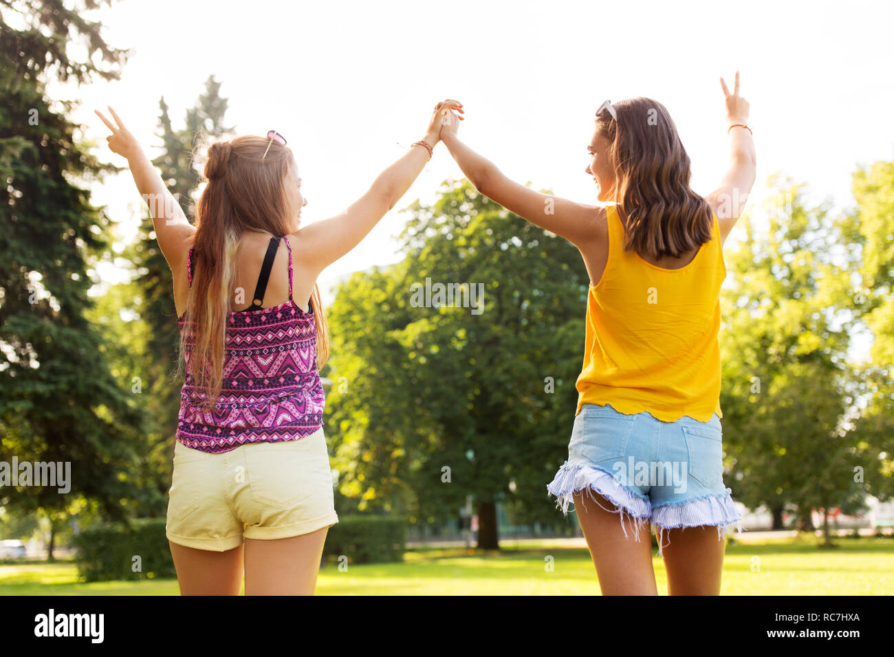 teenage girls showing peace hand sign at park Stock Photo - Alamy