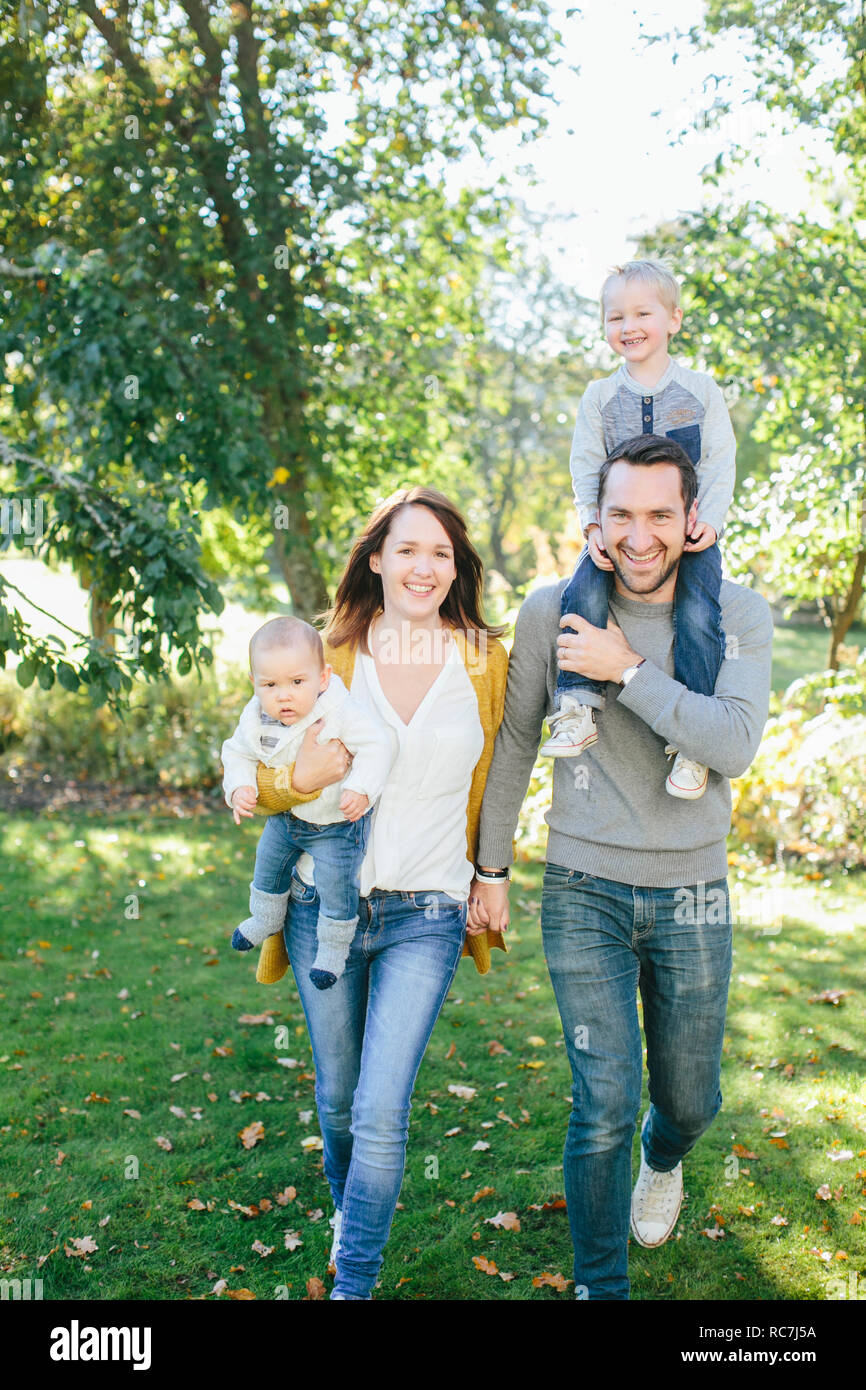 Family with two children walking through park Stock Photo - Alamy