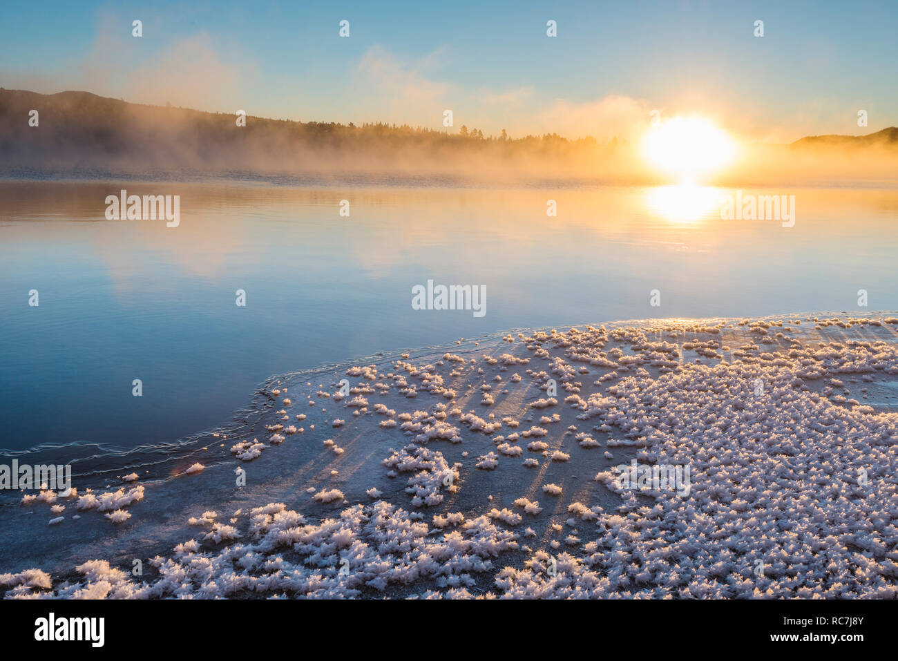 Sun over lake in winter scenery Stock Photo - Alamy