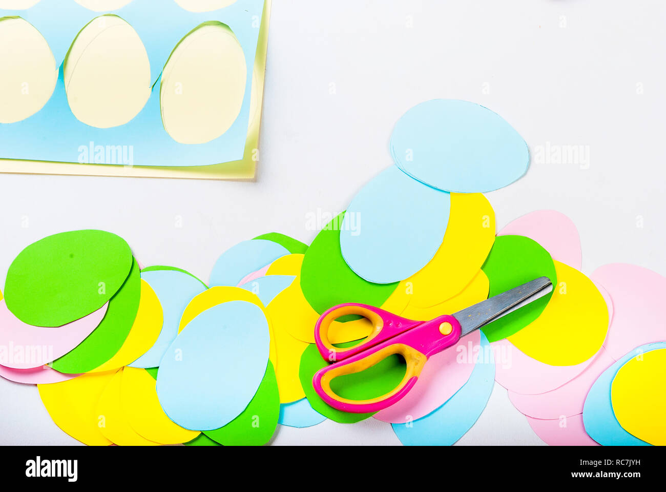Many Easter paper eggs, scissors and Sheets of colored paper. Child ...