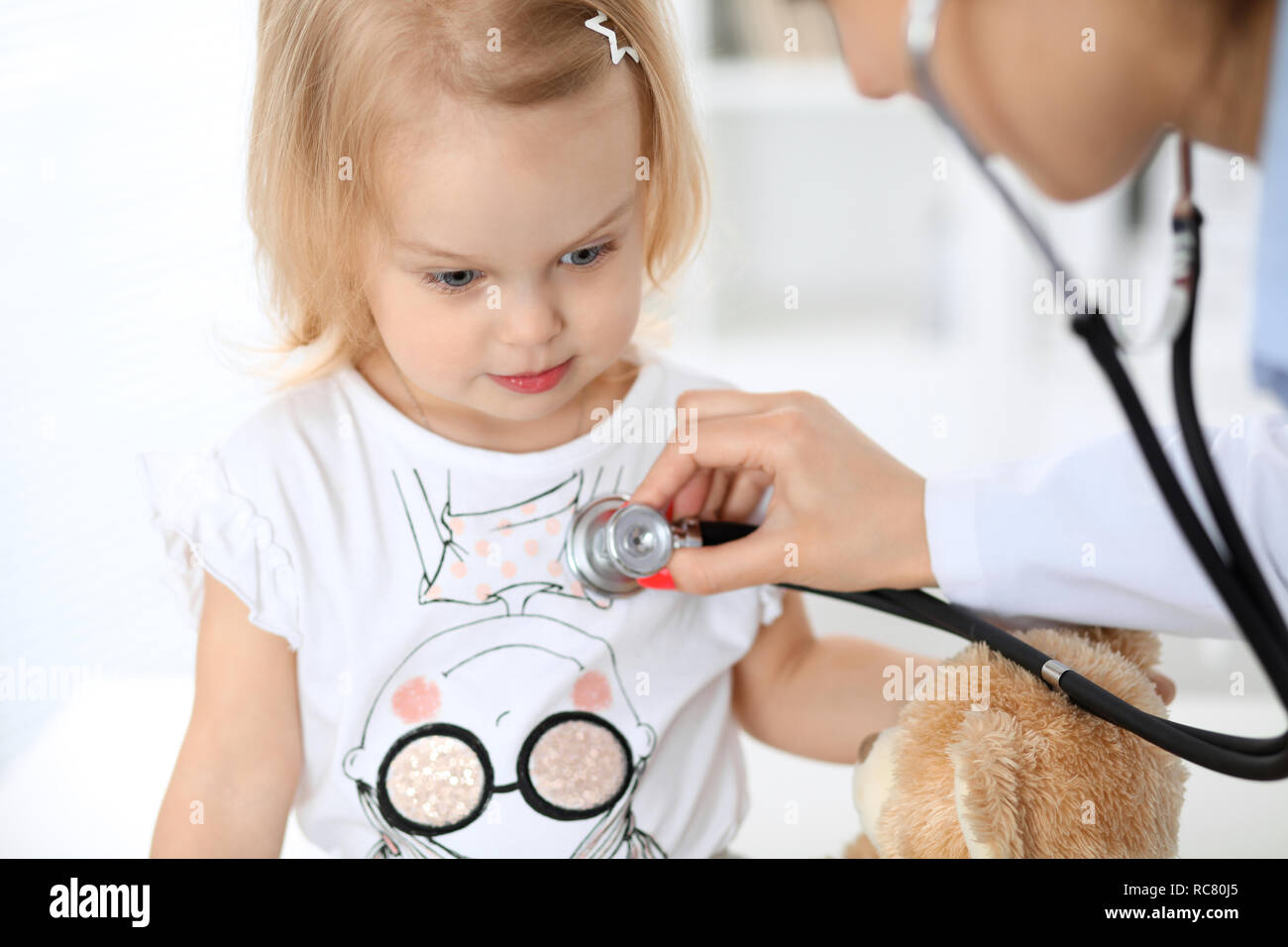 Doctor and patient baby in hospital. Little girl is being examined by ...