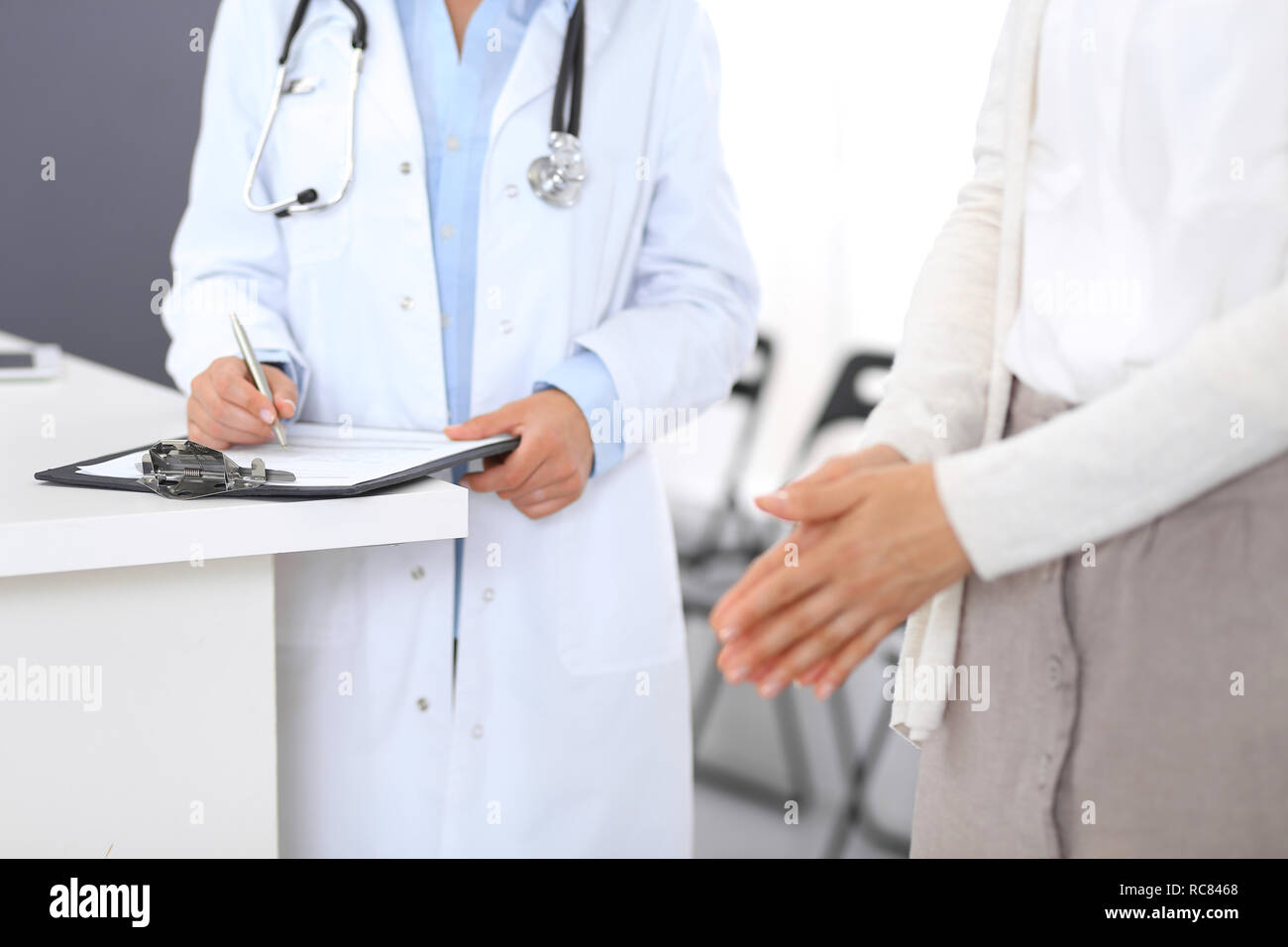 Unknown doctor and female patient discussing something while standing ...