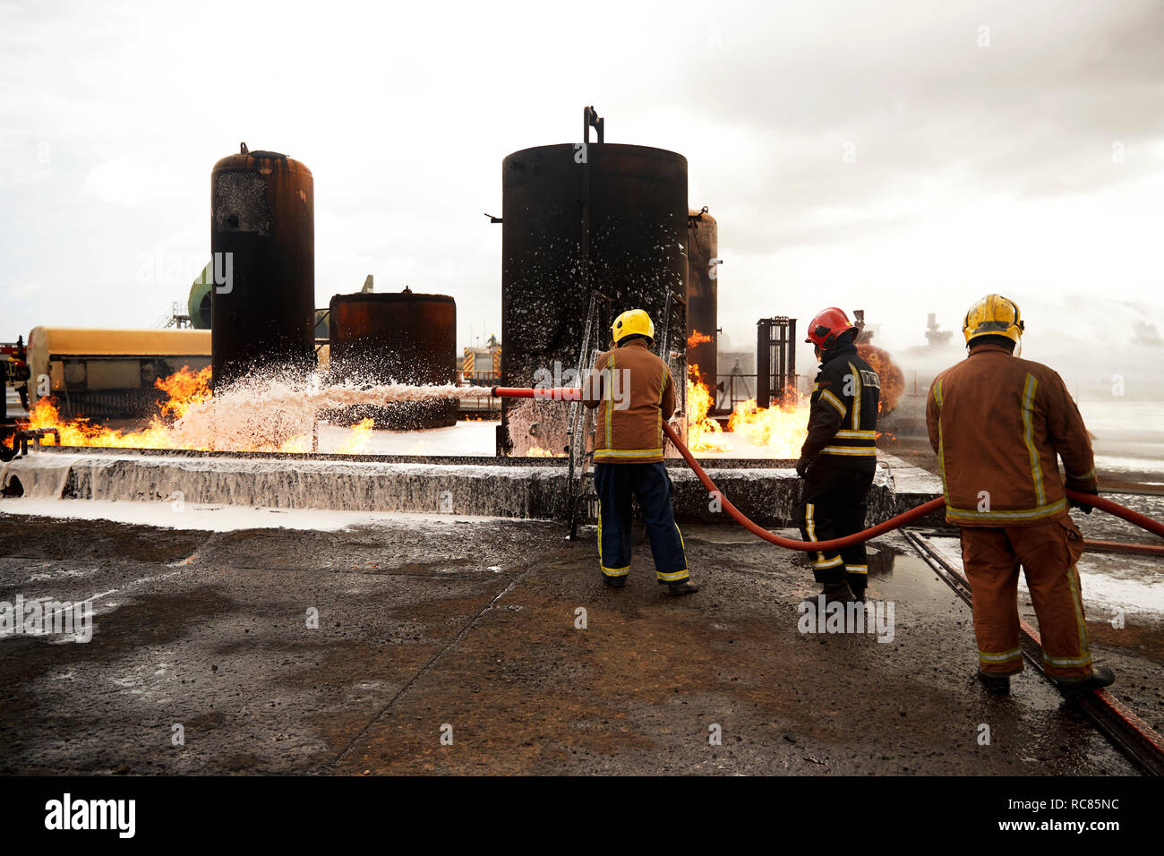 Firemen training, spraying firefighting foam onto oil storage tank fire ...