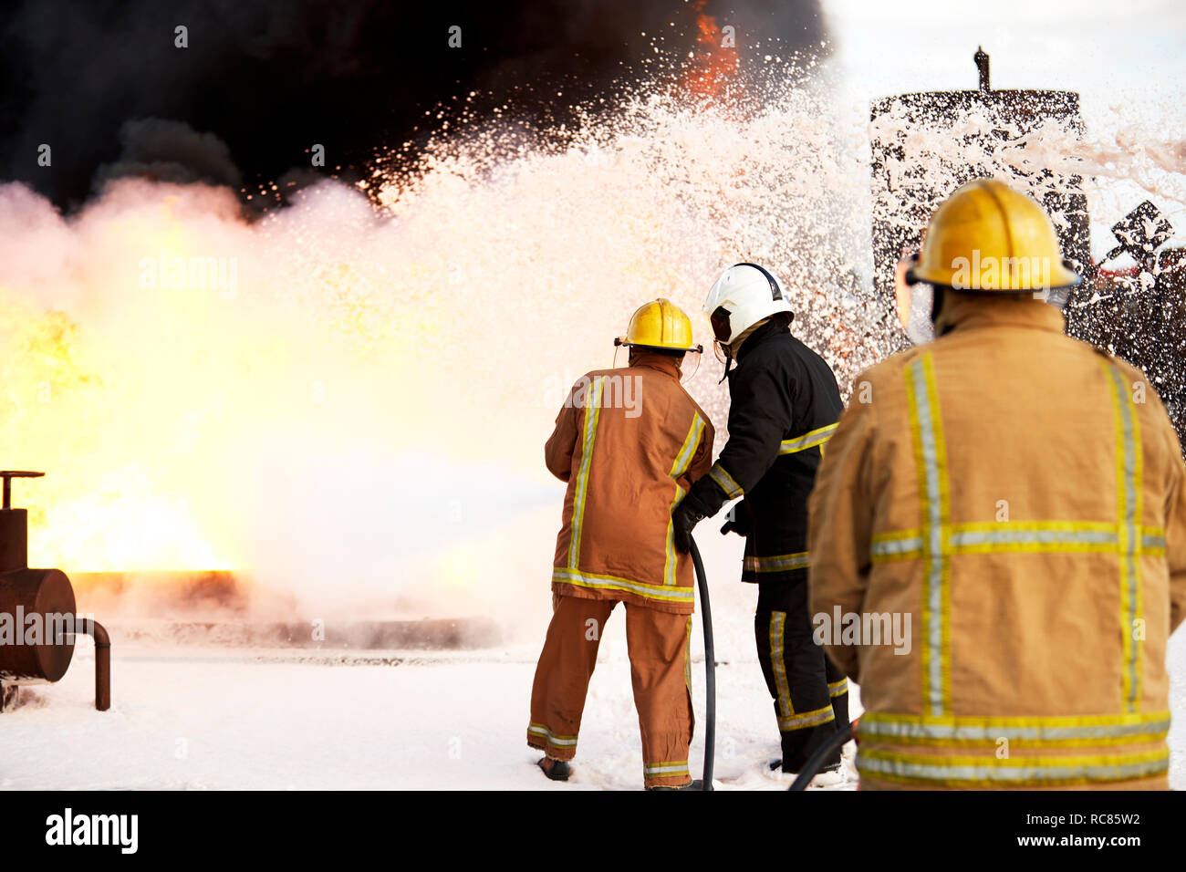 Firemen training, team of firemen spraying firefighting foam on fire at ...
