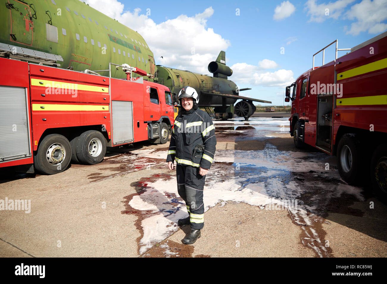 Fire training, fireman by fire engines at training facility, portrait ...