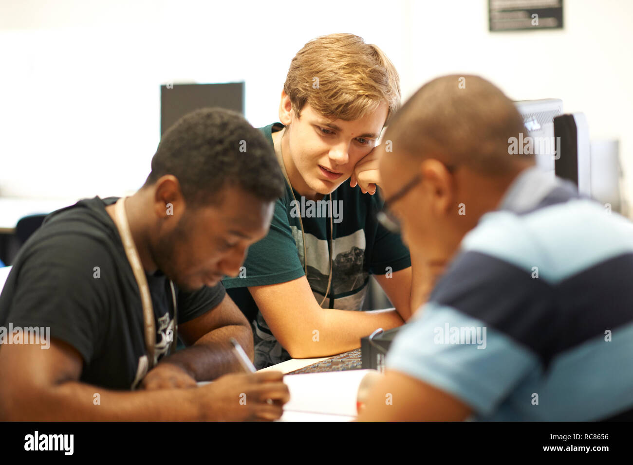 Male higher education students looking at paperwork in college ...