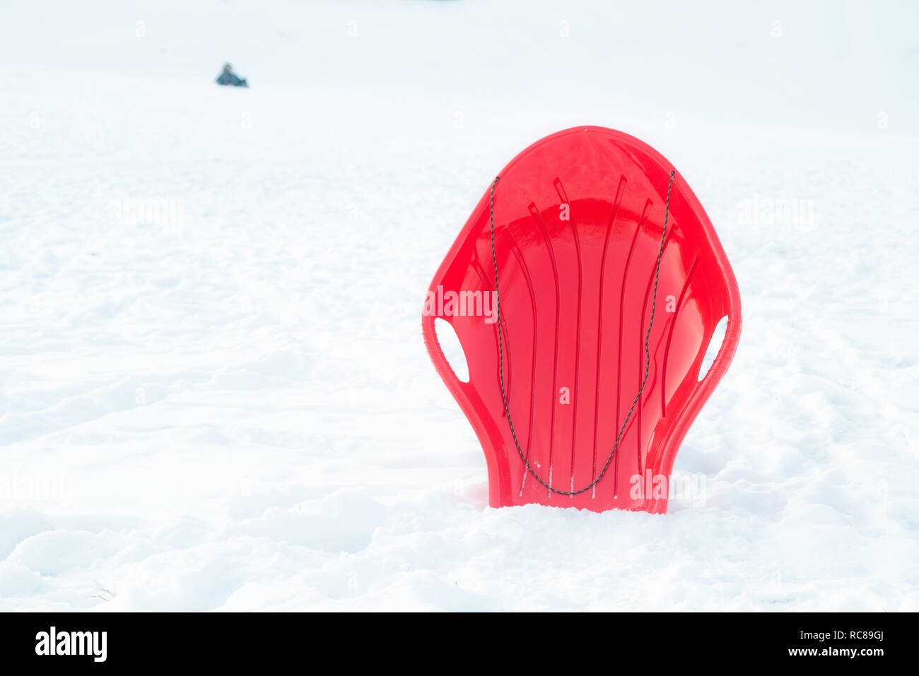 Red plastic sleigh, sledge, sled on white snowy background outdoors ...