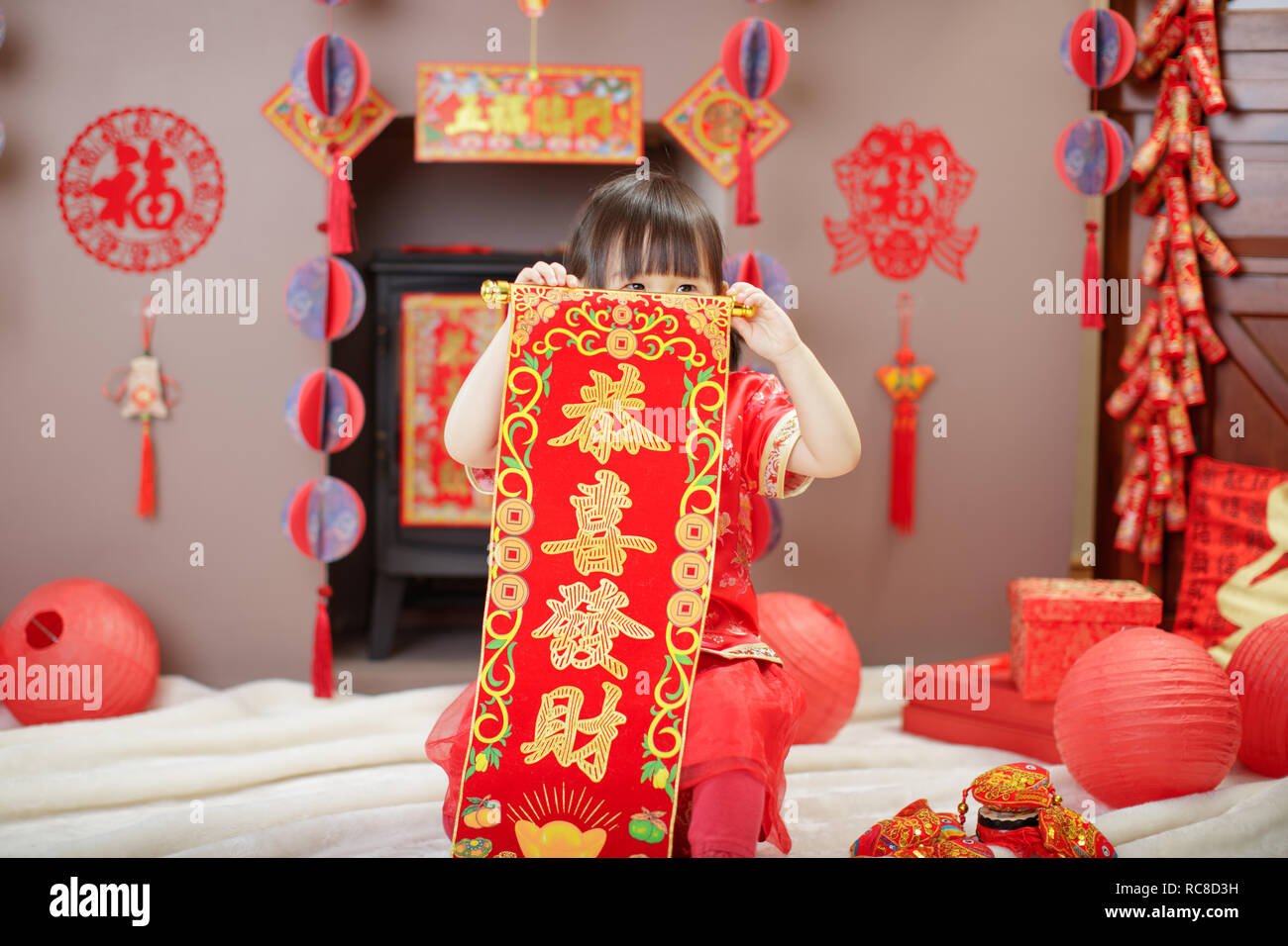 Chinese baby girl traditional dressing up with a Gong Xi Fa Cha scrolls ...