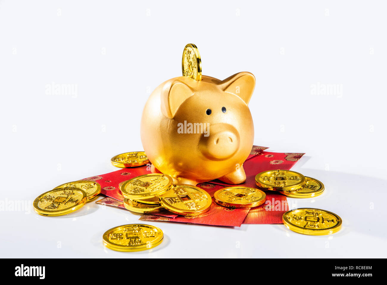 Piggy bank standing on red envelopes with golden coin isolated over ...