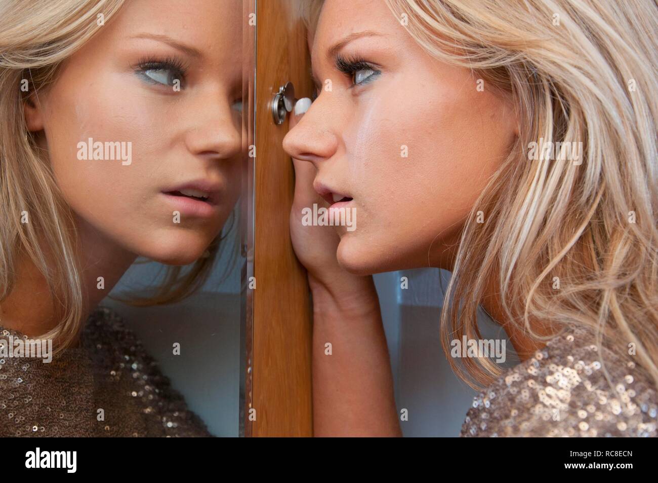 Young woman, 18-25 years, looking through hotel room door security spy ...