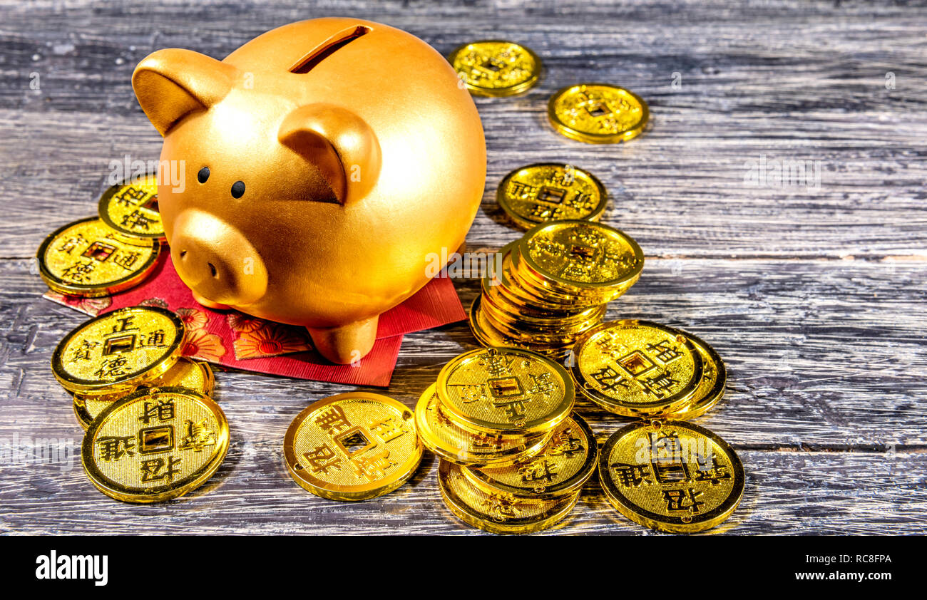 Piggy bank with golden coins and red envelopes on the wooden table ...