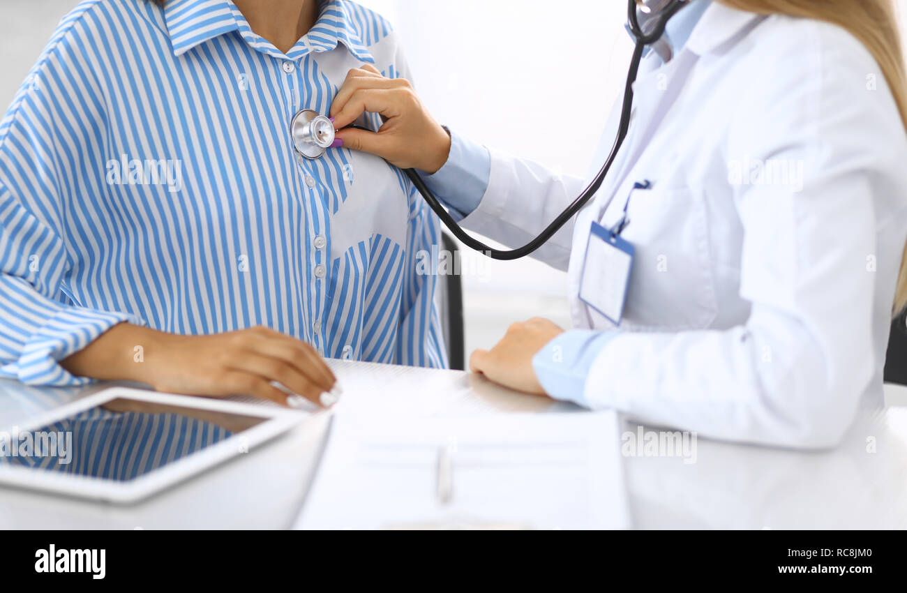 Doctor with a stethoscope in the hand. Physician examines her female ...
