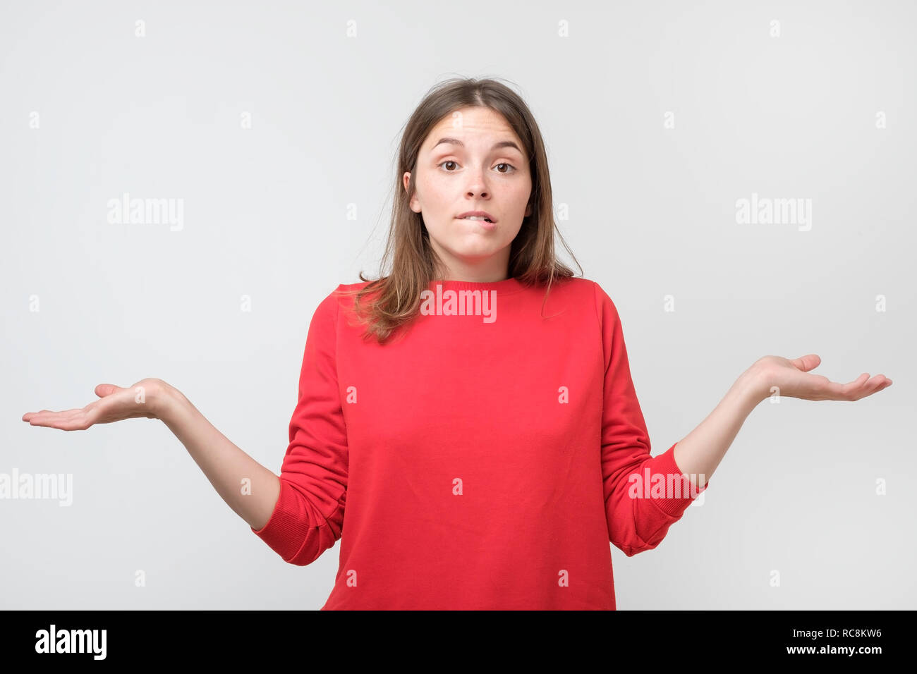 Clueless puzzled woman in red sweater with widely opened eyes having ...