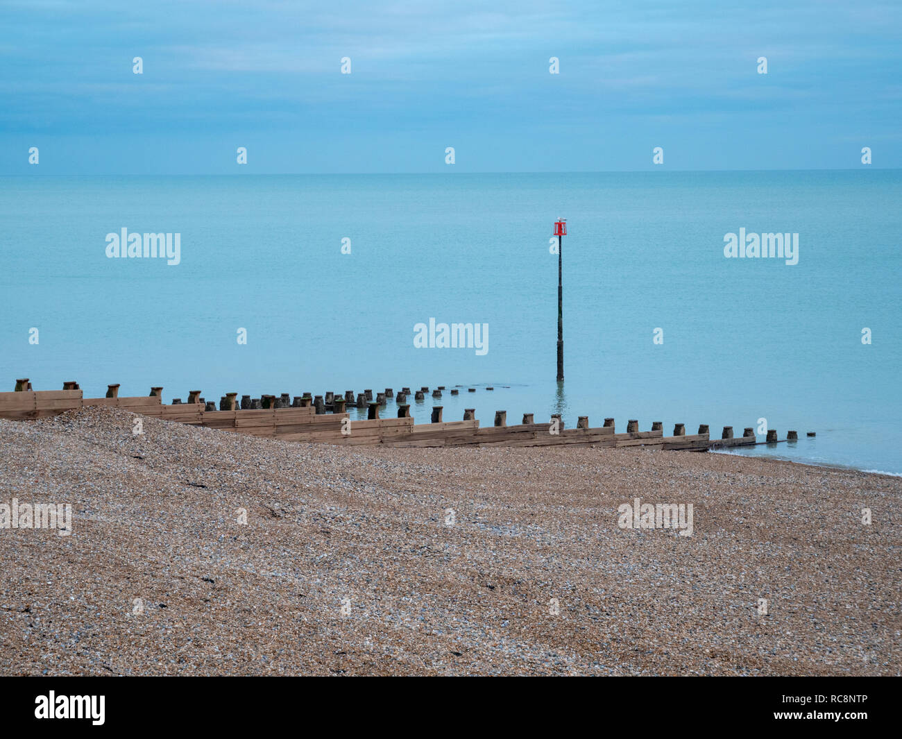 A view of a red marker post and groynes at the sshingle beach at ...