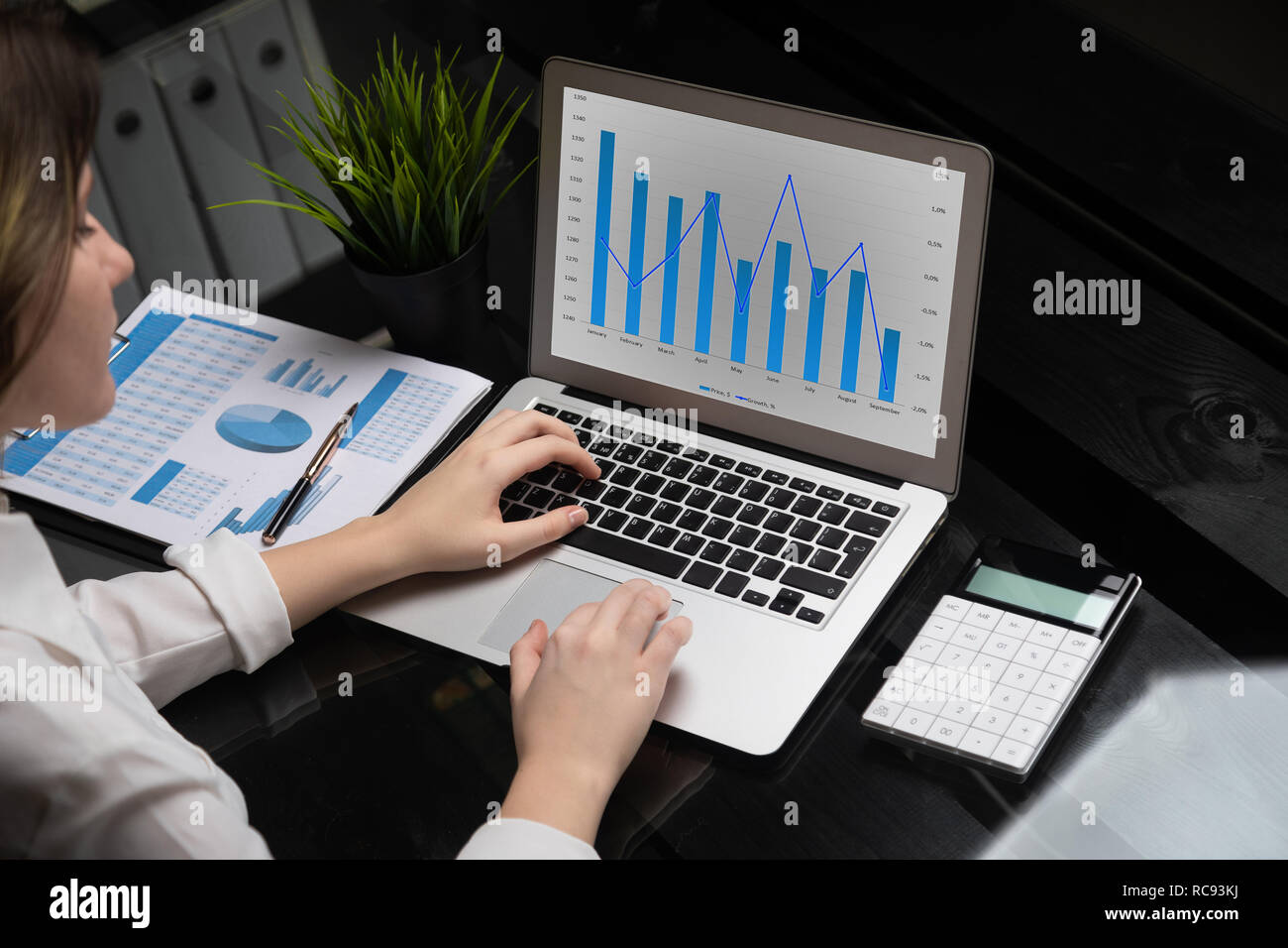 Freelancer typing on laptop with blank black screen next charts and ...