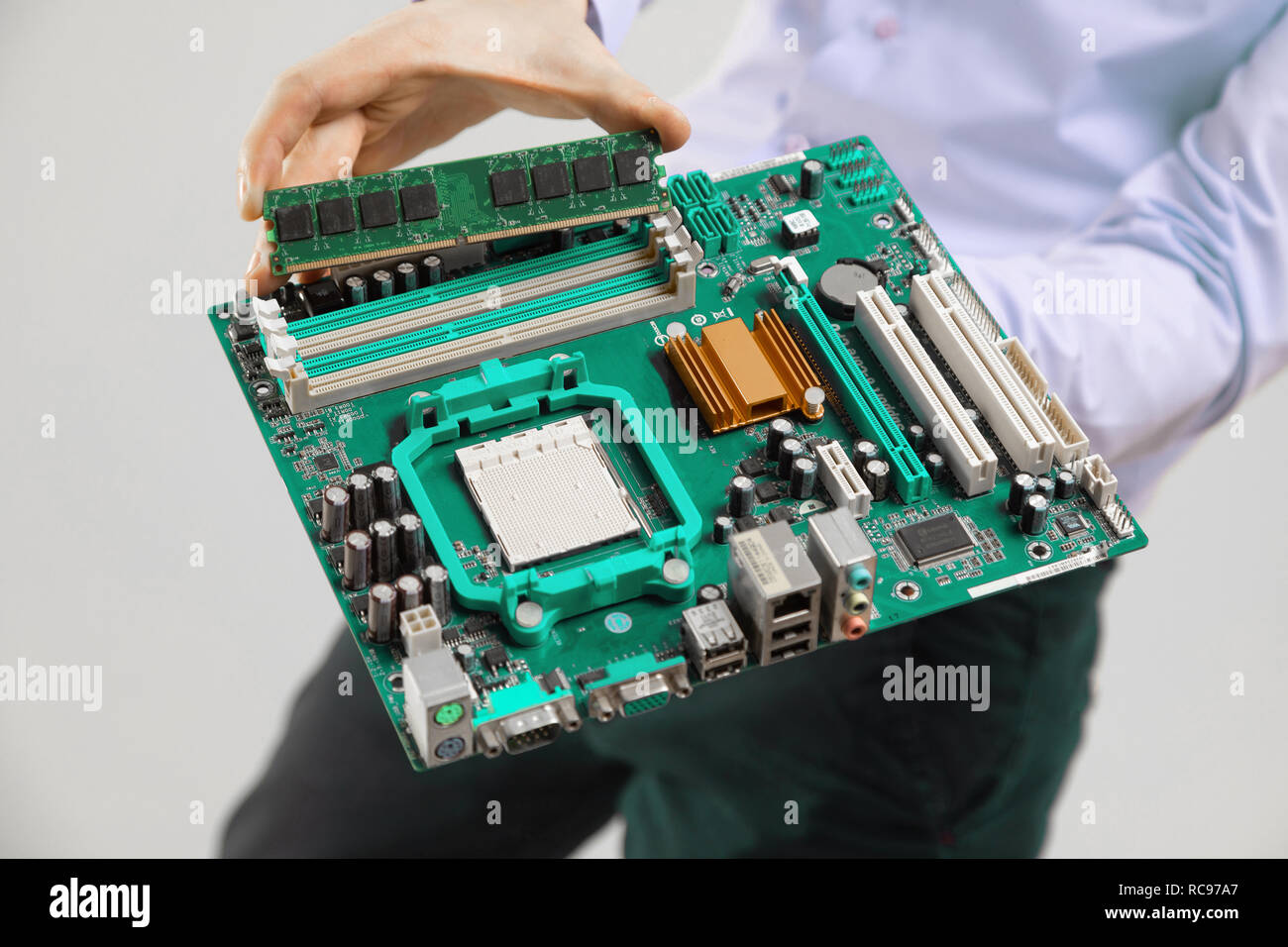RAM and motherboard in men's hands close-up isolated on light ...
