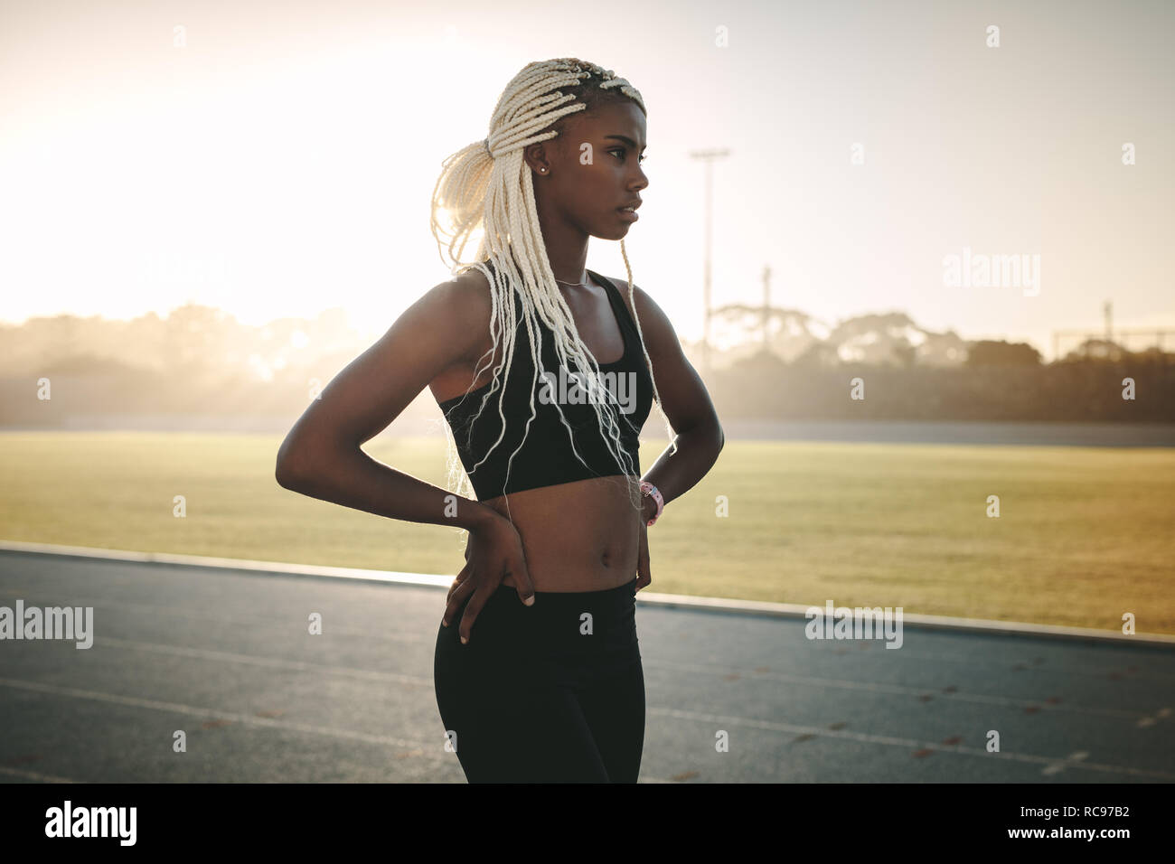 Side view of female athlete standing on an all-weather running track ...