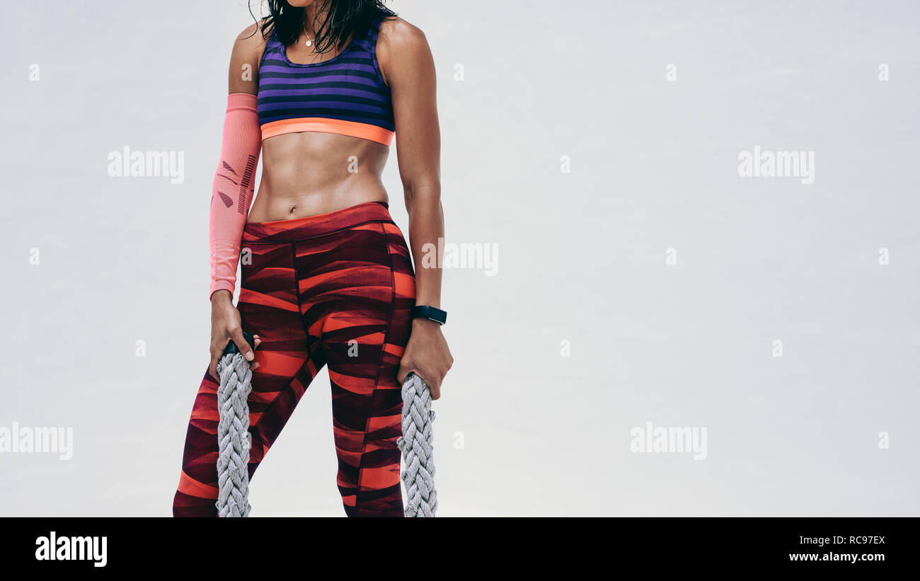 Athletic woman standing holding two battle ropes during workout ...