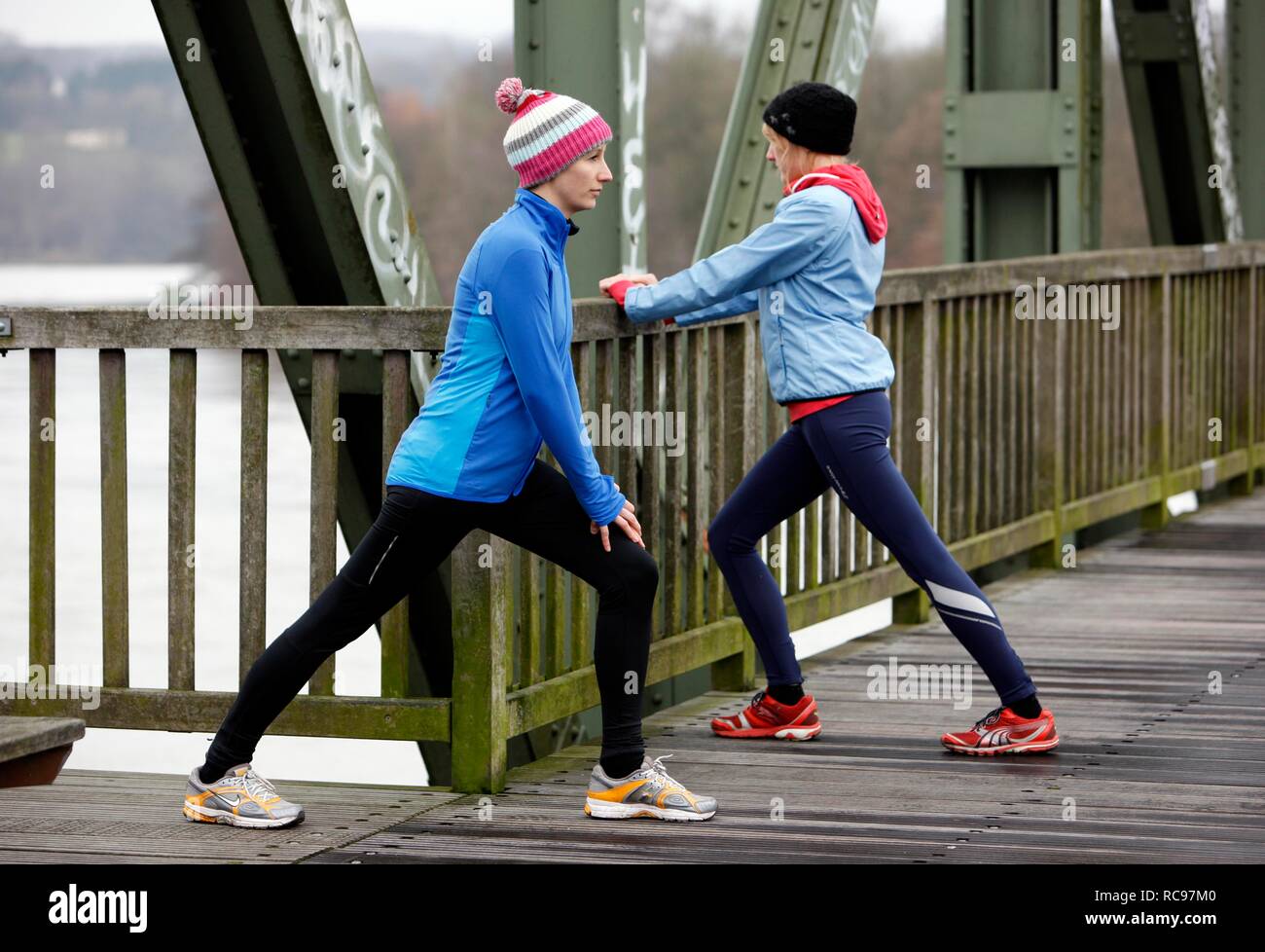 Two young women stretching after jogging in winter, wearing wind and ...