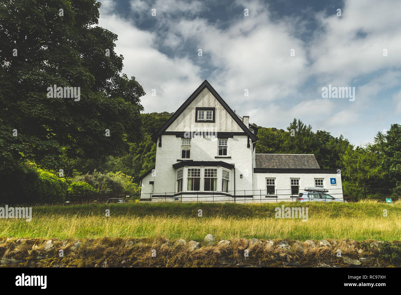 White traditional Irish house among trees and fields. Northern Ireland ...