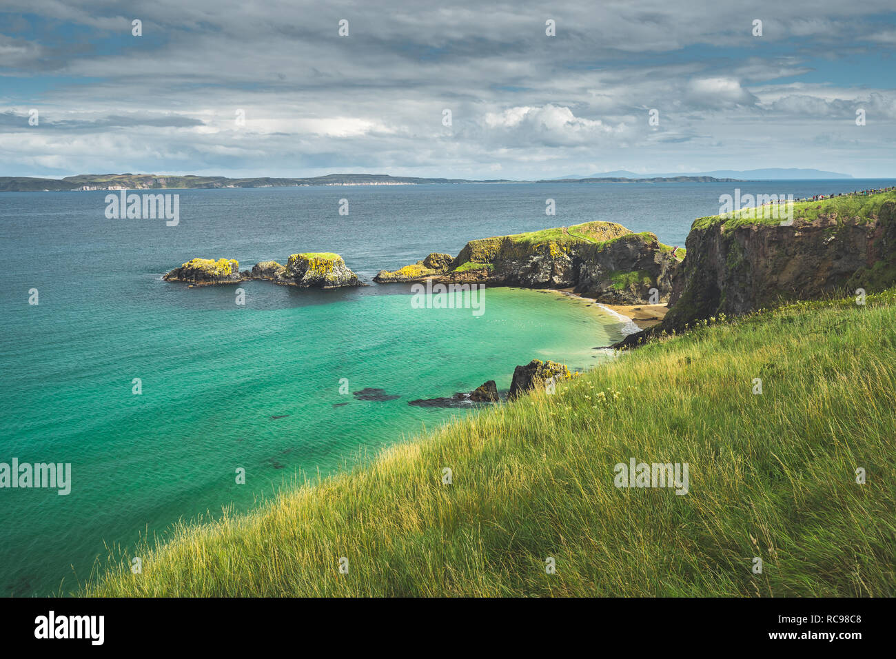 Irish bay with turquoise water and grass covered land. Northern Ireland ...