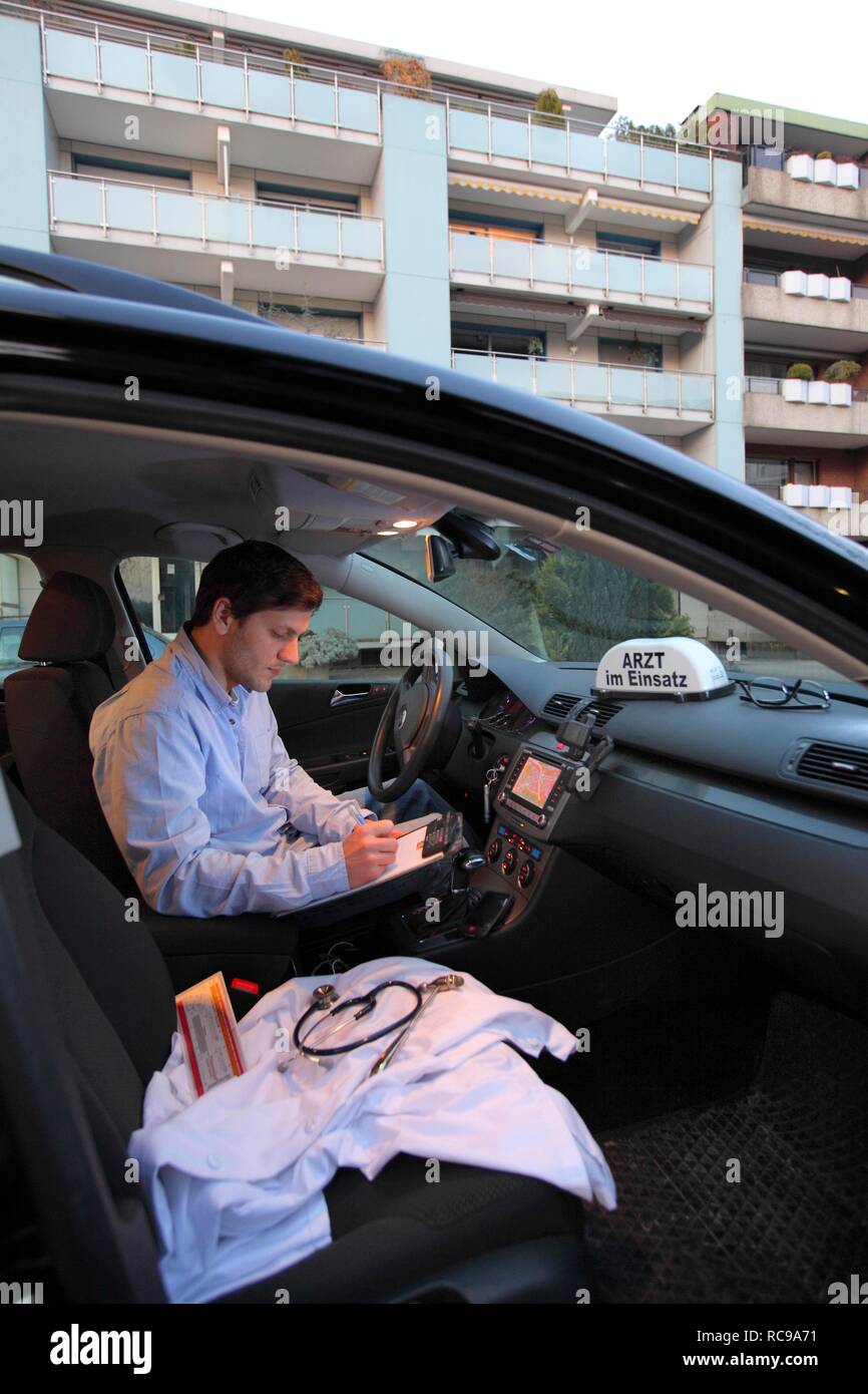 Young GP, general practitioner taking notes in his car after a home ...