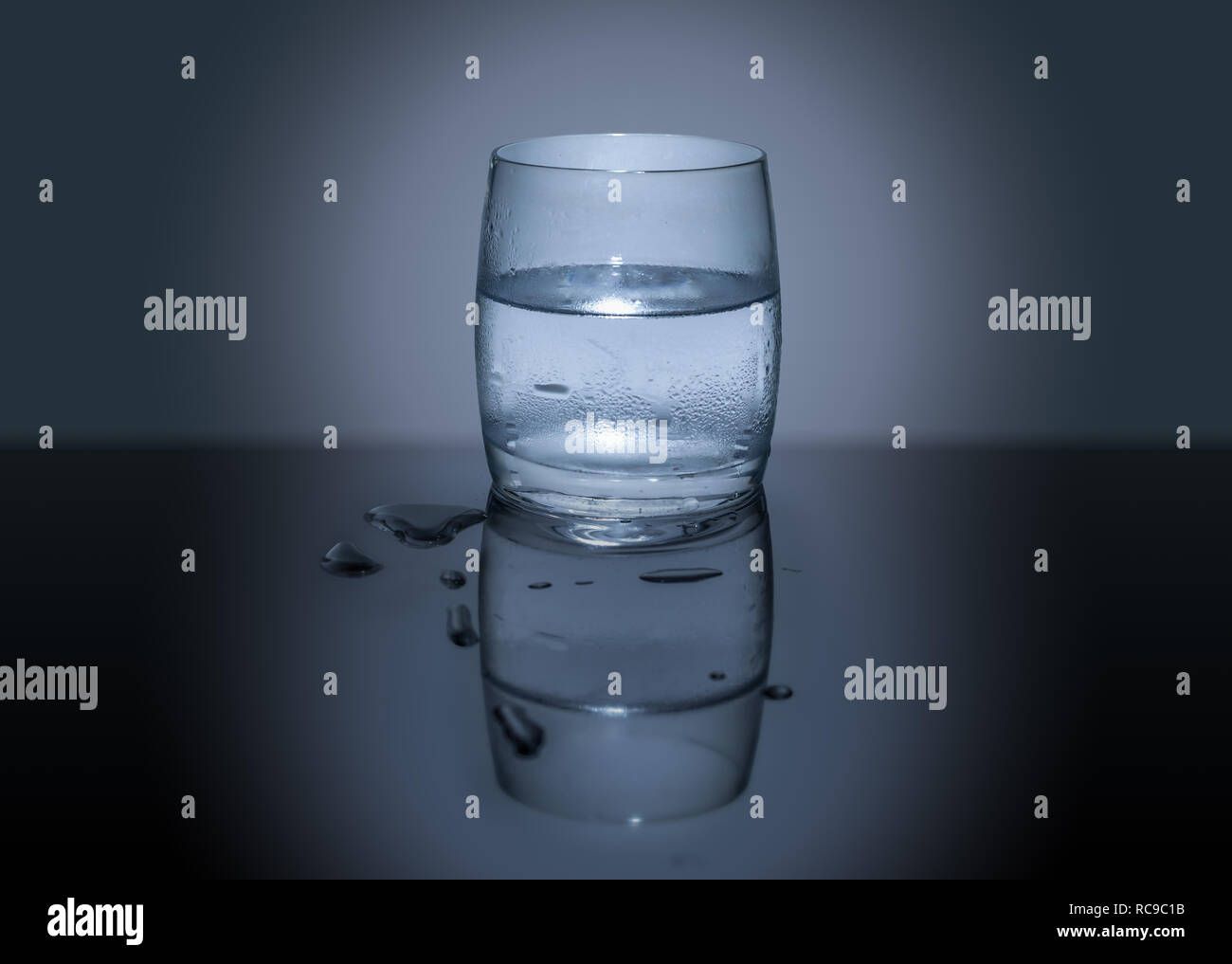 Fogged glass with cold water on reflecting table with drops of water in ...