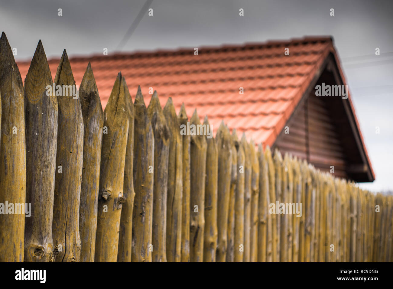 A fence made of sharp wooden stakes against the background of a wooden ...