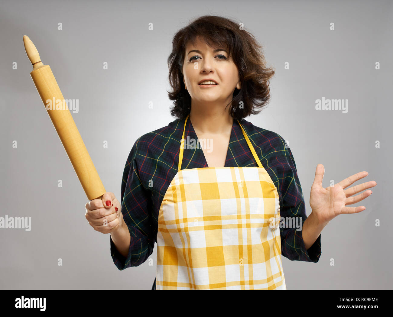 Baker lady with a wooden rolling pin over gray background Stock Photo ...