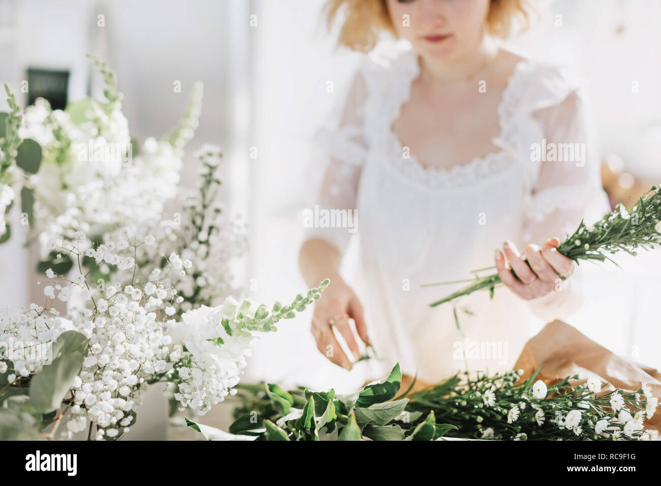 Young woman in white dress arranging white flowers, mid section Stock ...