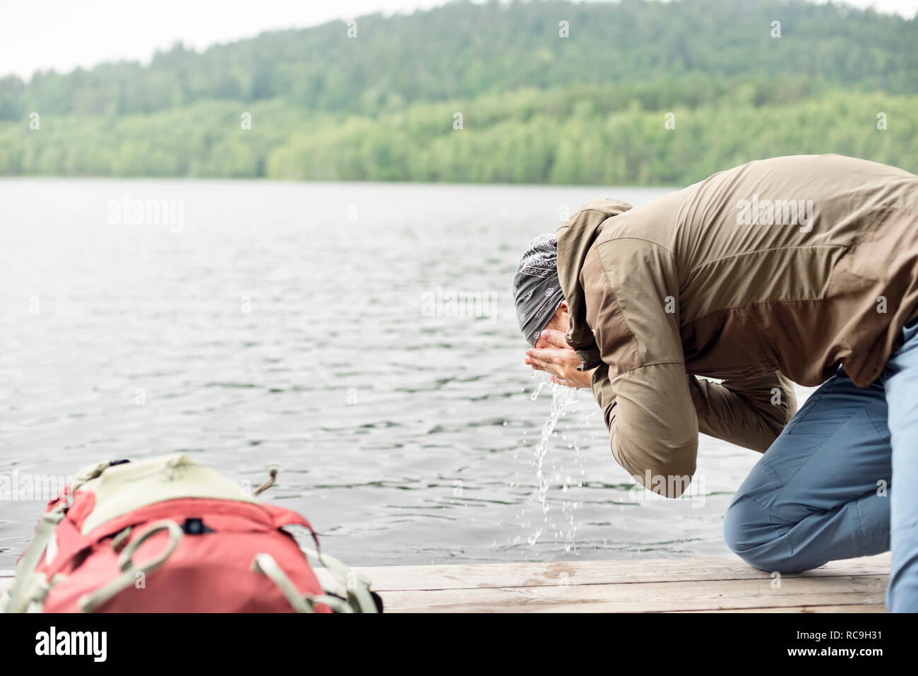 Hiker washing face in lake Stock Photo - Alamy