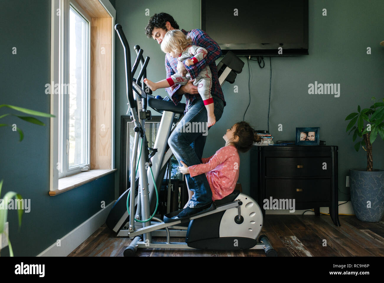 Father and children playing on elliptical machine Stock Photo - Alamy