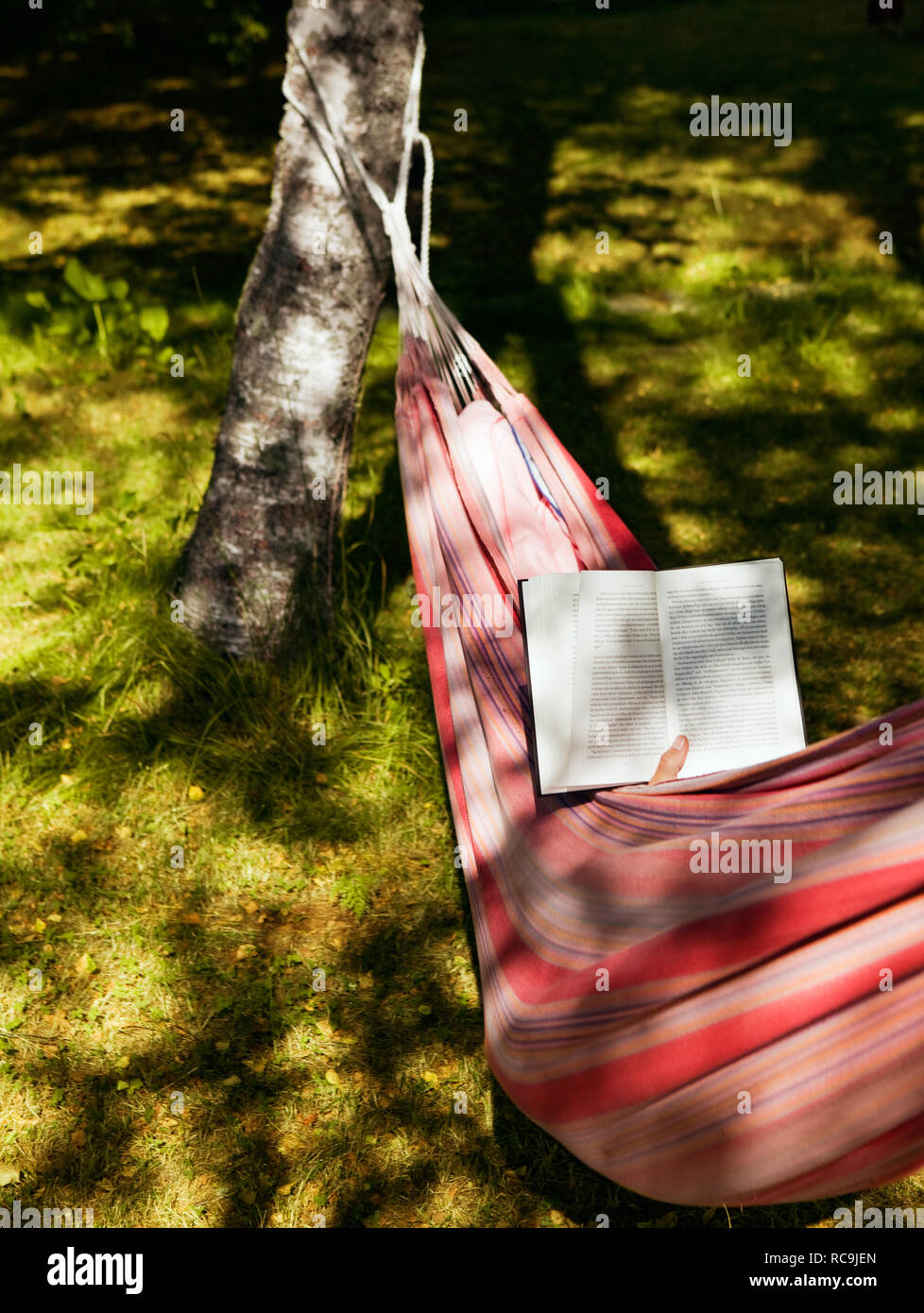 Person on hammock reading book Stock Photo - Alamy