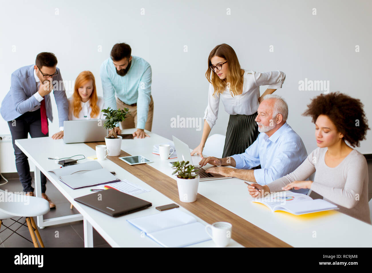 View at group of young multiracial business people around table during ...