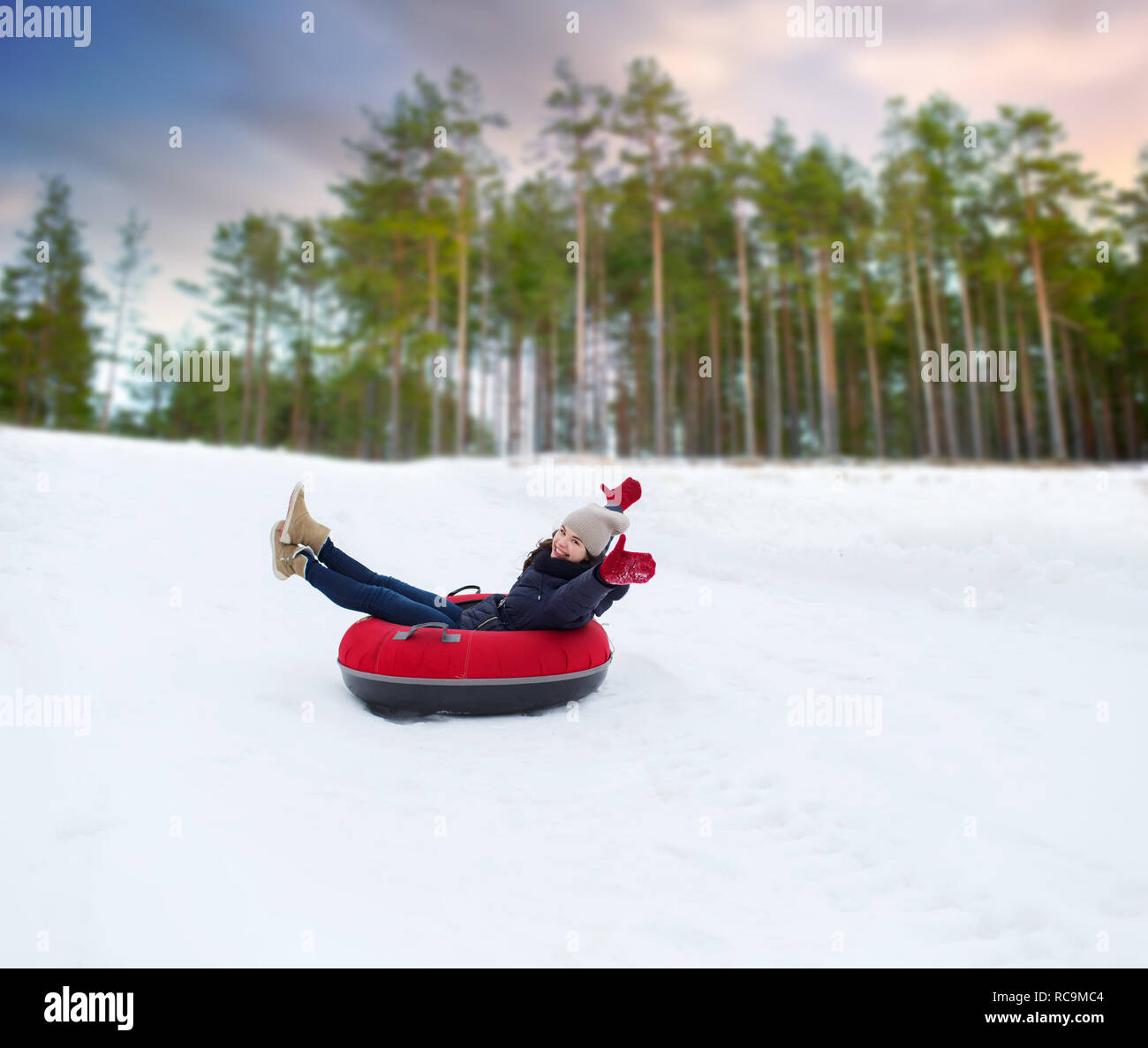 happy teenage girl sliding down hill on snow tube Stock Photo - Alamy