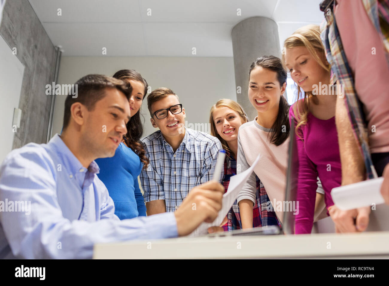 students and teacher with papers and laptop Stock Photo - Alamy