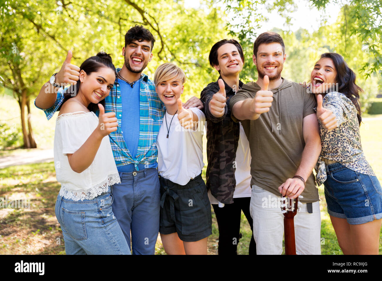 friends with guitar showing thumbs up at park Stock Photo - Alamy