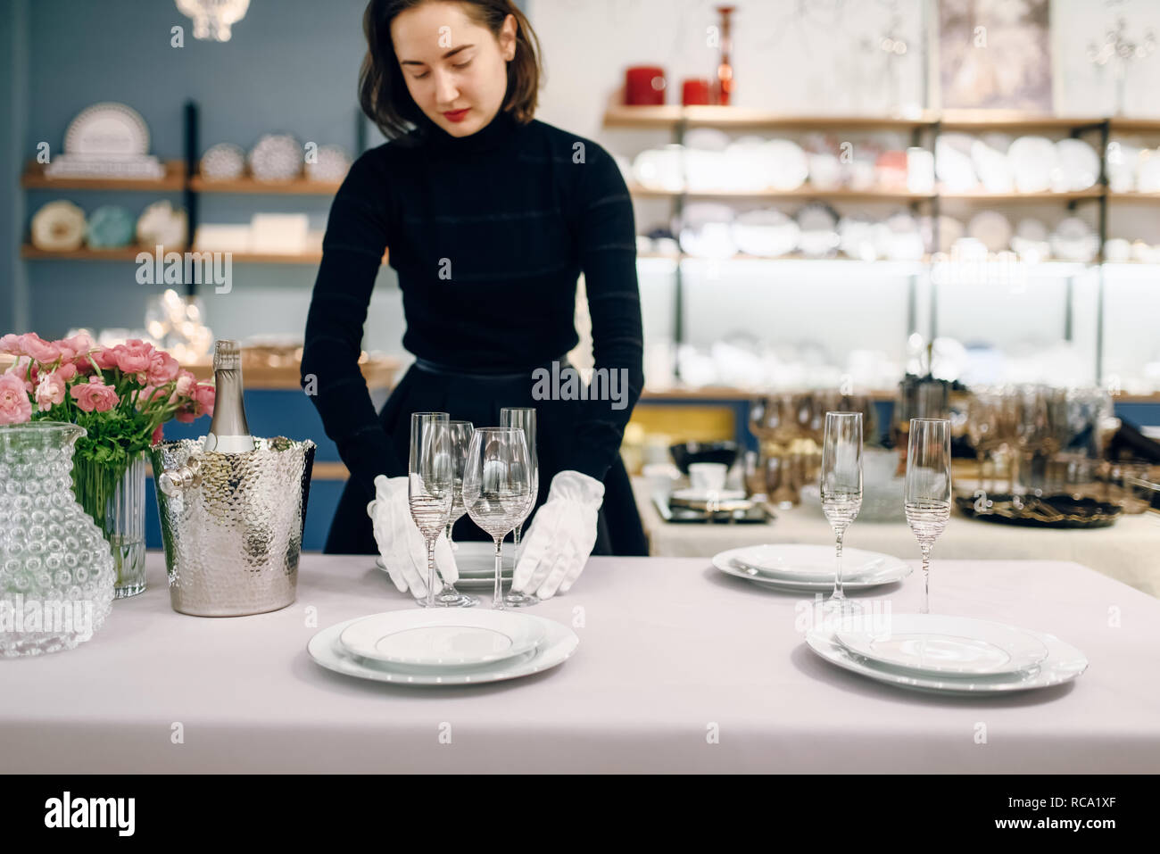 Waitress in gloves puts the dishes for dining, table setting. Serving ...