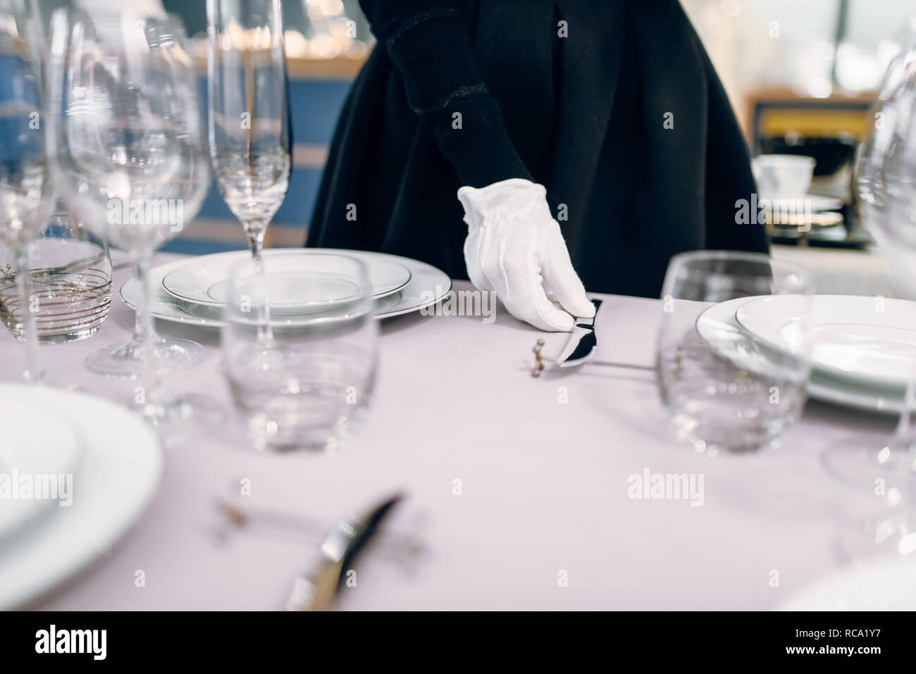 Waitress in gloves puts the knife, table setting. Serving service ...
