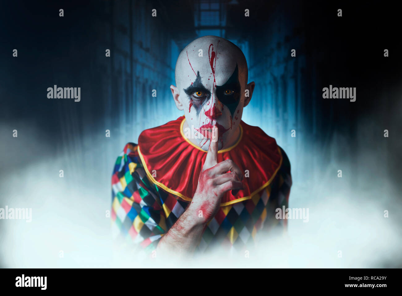 Portrait of mad bloody clown shows the quiet sign, face in blood. Man ...