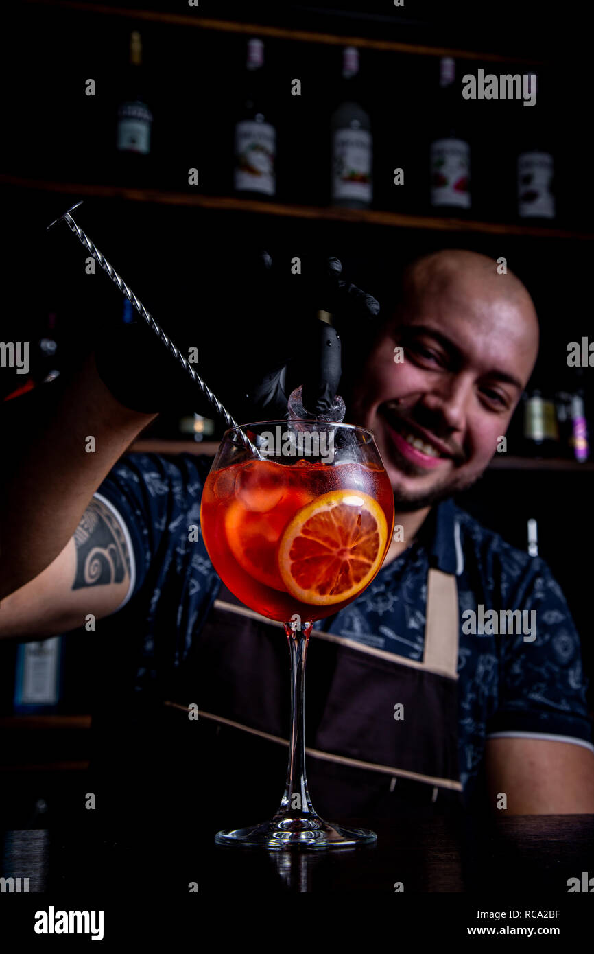 Barman puting to glass of fresh and tasty Aperol syringe cocktail peace ...