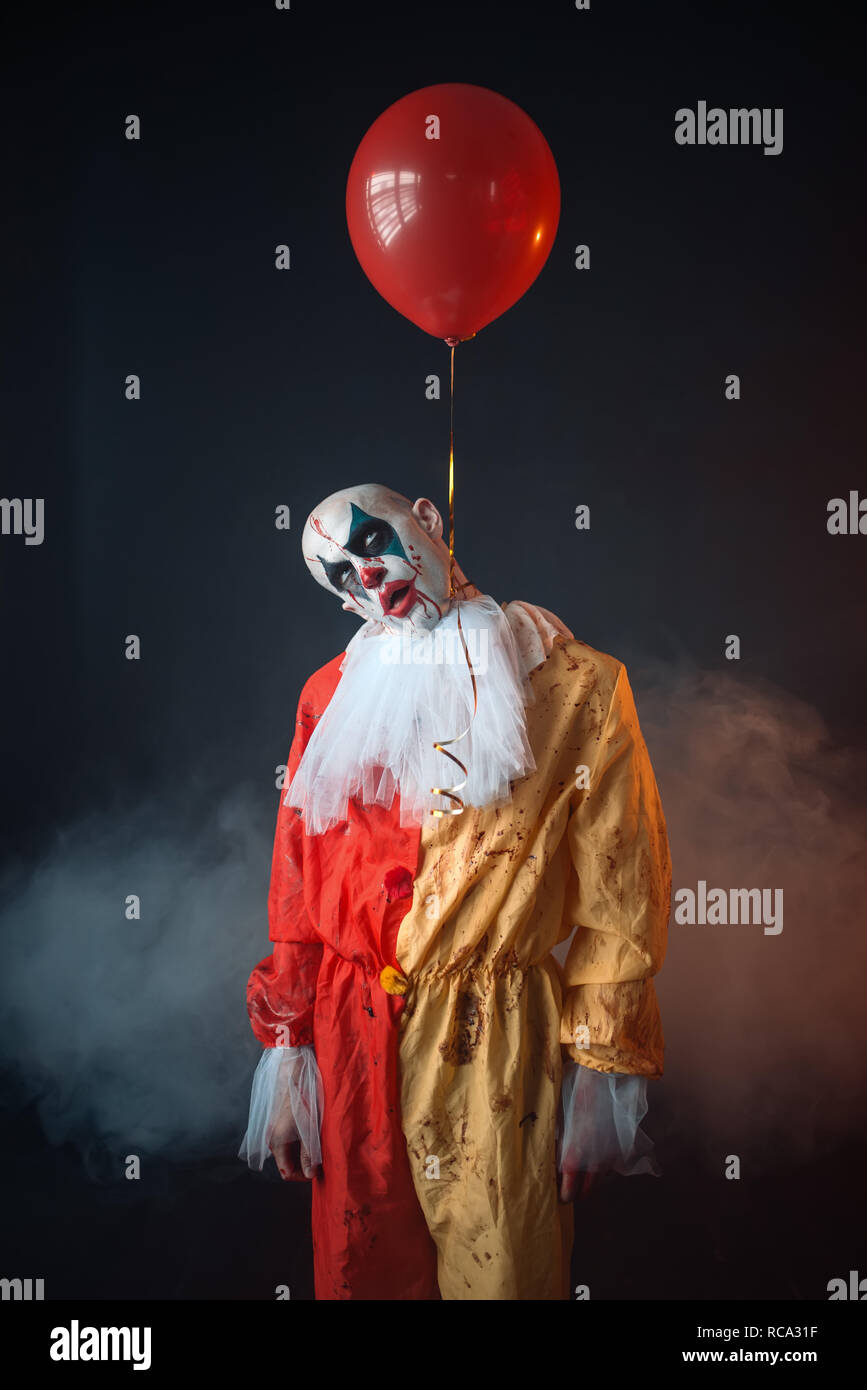 Mad bloody clown with makeup in carnival costume hung himself on air ...