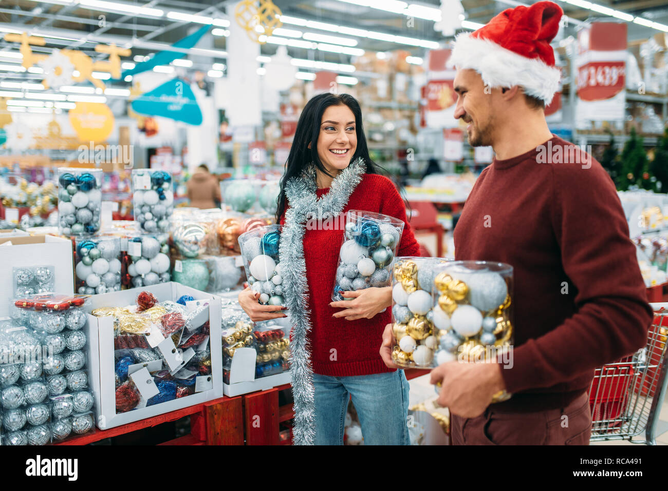Young couple with boxes full of Christmas balls in shop, family ...