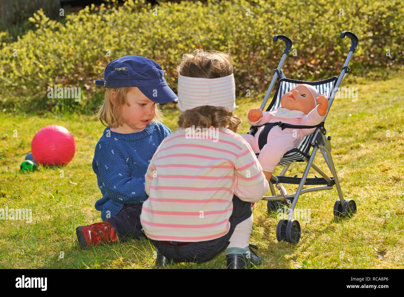 zwei kleine Mädchen, 2 Jahre alt, spielen mit einer Puppe im ...