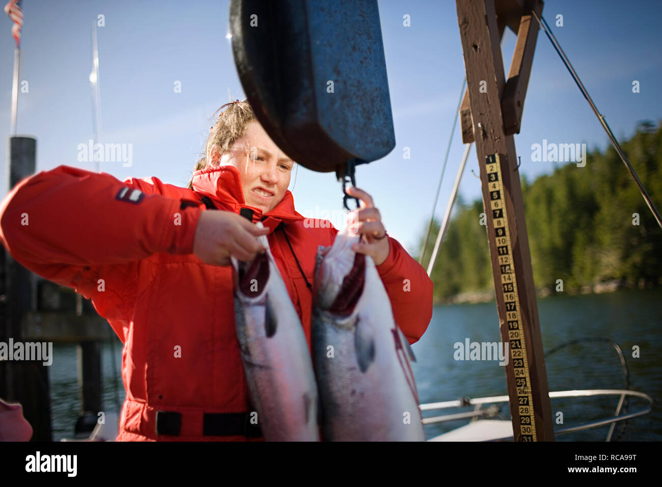 Teenage girl lifting two fish up to be weighed Stock Photo - Alamy