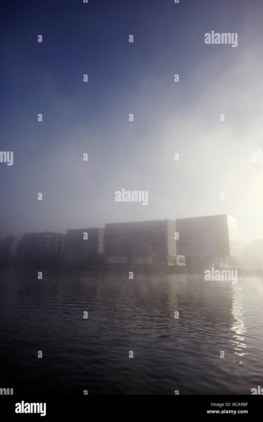 Buildings at water in fog Stock Photo - Alamy